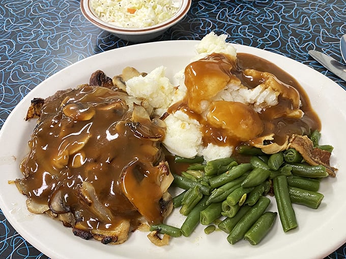Comfort food perfection: chopped sirloin smothered in mushroom gravy alongside mashed potatoes and green beans. Grandma would approve—and maybe be a little jealous.