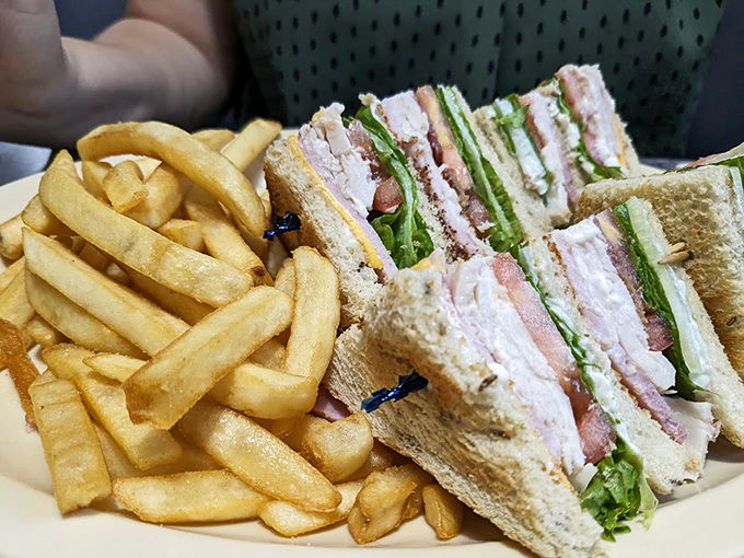 This club sandwich isn't just stacked with layers—it's stacked with tradition, served with a side of golden fries that crackle with each bite.