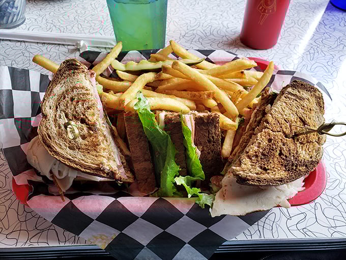 The club sandwich—architecture you can eat. Three perfectly toasted stories of satisfaction with golden fries as the perfect next-door neighbors.
