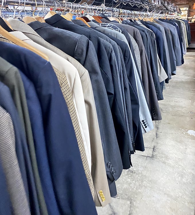 The men's suit section—a navy blue sea of possibility. One man's "doesn't fit anymore" becomes another's "best job interview outfit ever."