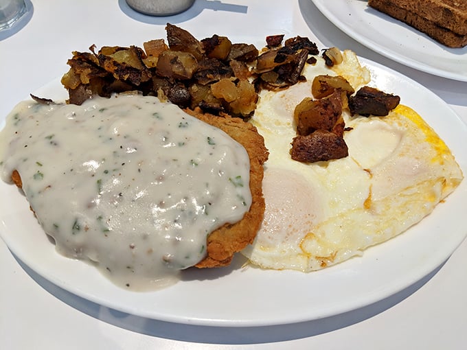 Country fried steak smothered in gravy alongside sunny-side-up eggs—a breakfast so hearty it could fuel a cattle drive or just your morning commute.