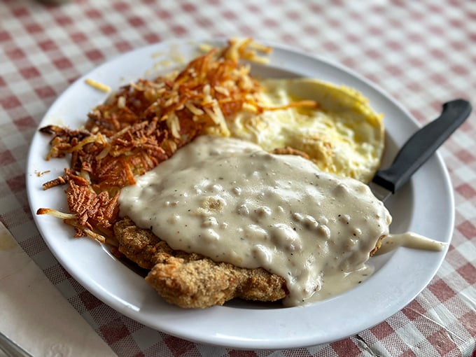 Country fried steak smothered in that signature gravy with crispy hash browns—a plate that says "your diet starts tomorrow" in the most delicious way possible.. country fried steak