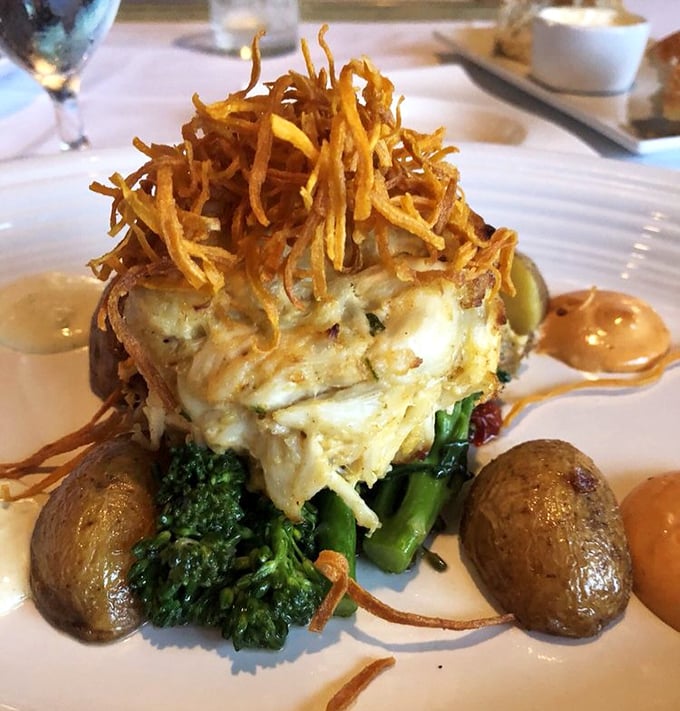 Not your grandmother's crab cake—this towering creation with crispy crown sits atop vibrant vegetables like Neptune's scepter.