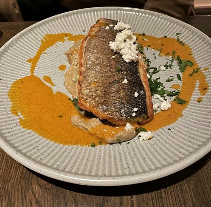 The crispy branzino arrives like a work of art – crisp skin, tender flesh, and a sauce so good you'll consider drinking it straight.