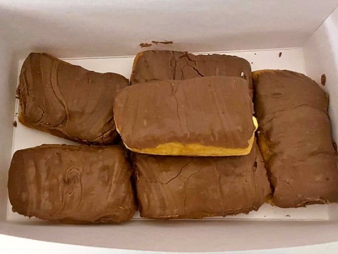 Long Johns lined up like delicious chocolate-covered submarines. These aren't just eclairs—they're vessels of joy waiting to transport you to happiness.