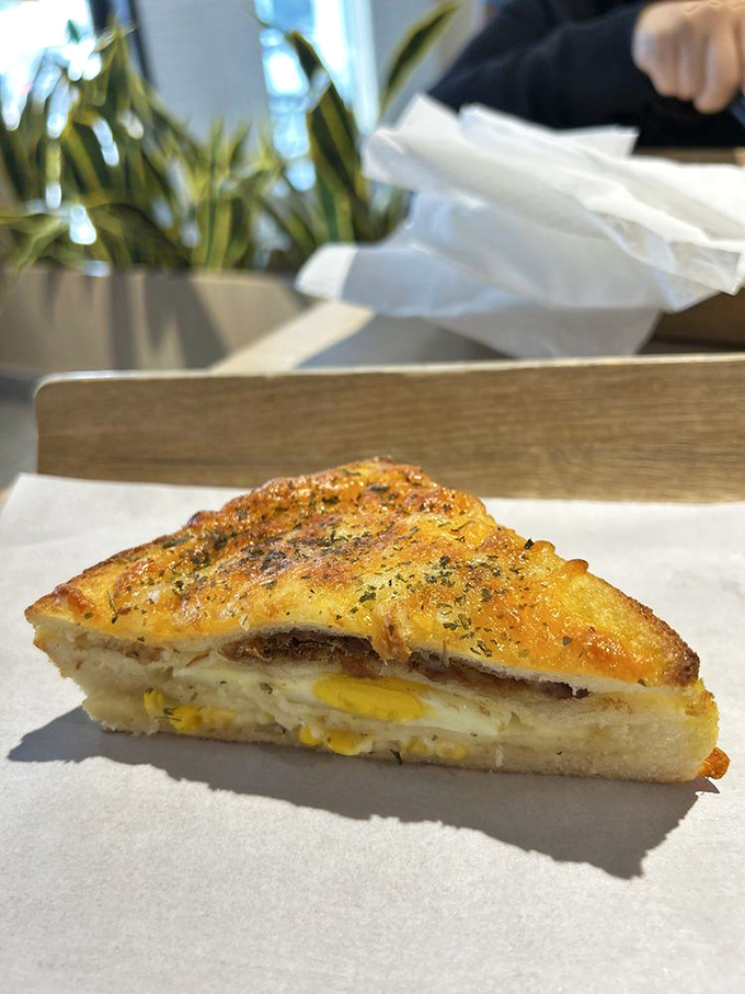This isn't your sad desk lunch sandwich. Perfectly grilled bread hugging eggs and corn like they're family—because in the food world, they are.