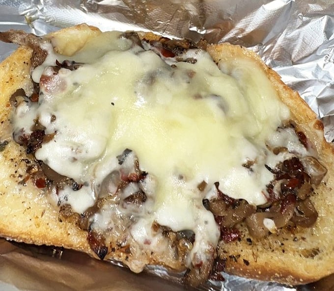 This open-faced sandwich isn't just topped with cheese – it's wearing a magnificent melted crown. Comfort food royalty served on humble aluminum foil.
