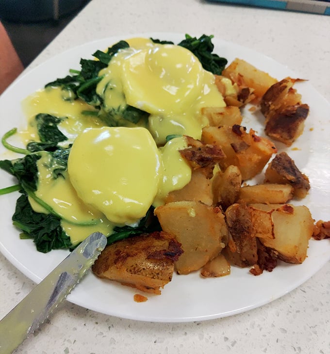 Eggs Benedict done right is breakfast's highest achievement—these poached perfections swimming in hollandaise prove someone in that kitchen genuinely cares about your morning.