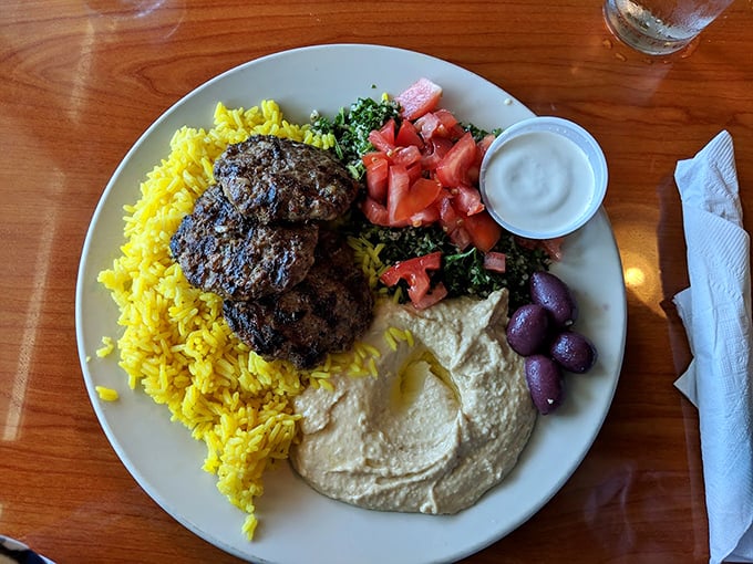 The kofta platter arrives like a complete Mediterranean vacation on a single plate. Yellow rice, hummus, tabbouleh—a passport isn't required.