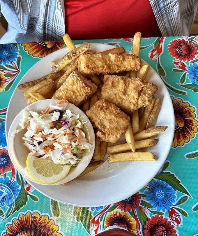 Golden-battered fish that shatters with each bite, alongside perfectly crisp fries and fresh slaw – the holy trinity of coastal comfort food.