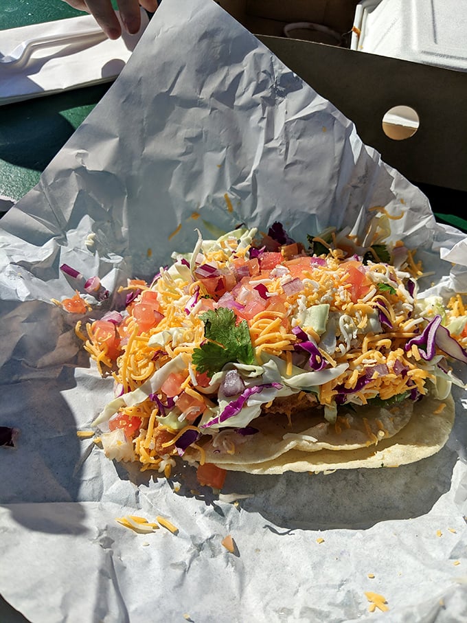 A rainbow of fresh ingredients transforms this simple taco into edible art—purple cabbage, yellow cheese, and green cilantro creating a fiesta for your taste buds.