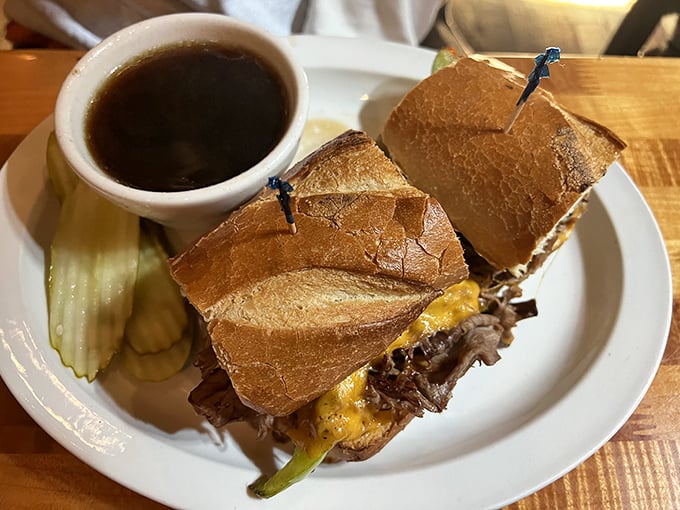 The French Dip sandwich – where thinly sliced beef meets crusty bread in a marriage blessed by a cup of savory au jus. Pickle on the side for good measure.