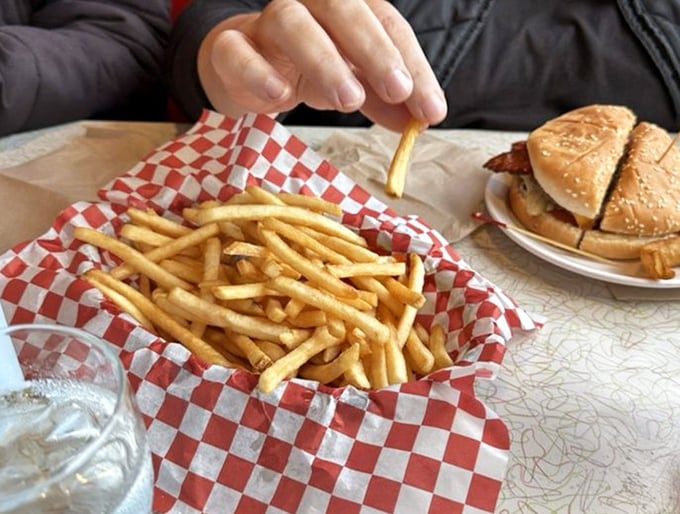Golden, crispy french fries served in classic red checkered paper – the perfect supporting actor to the burger's starring role.