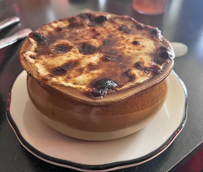 This isn't just French onion soup—it's a geological wonder with a molten cheese cap that requires strategic drilling to reach the savory broth below.