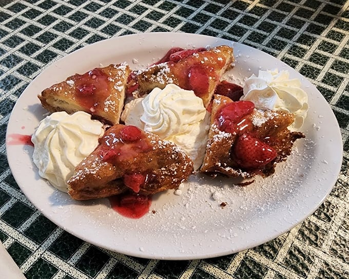 French toast that's crossed the line from breakfast to dessert, crowned with strawberries and whipped cream. Your diet plan just called—it's taking the day off.