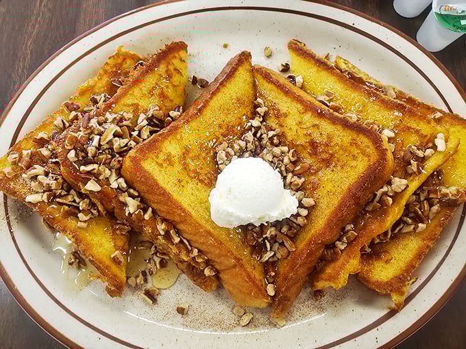 French toast that could make you weep – golden-brown perfection topped with pecans and a dollop of whipped butter melting into every crevice.