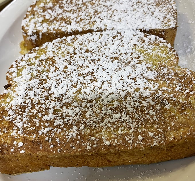 French toast dusted with powdered sugar sits like a golden island on the plate – simple perfection that needs no passport to transport you to breakfast bliss.