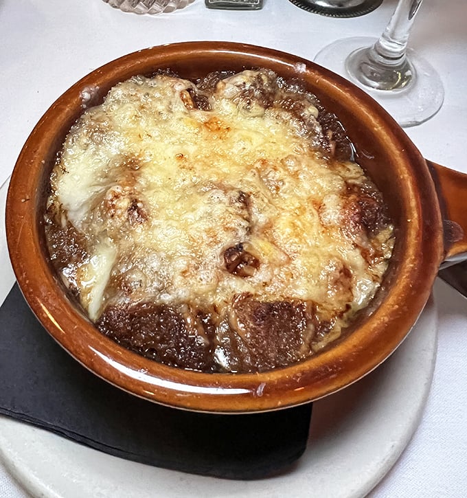 The French onion soup arrives bubbling hot, its cheese canopy stretching with each spoonful like the finale of a delicious magic show.