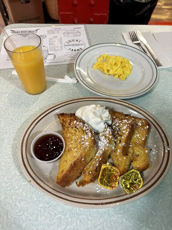 French toast perfection: golden slices dusted with powdered sugar, accompanied by whipped cream and pure maple bliss.
