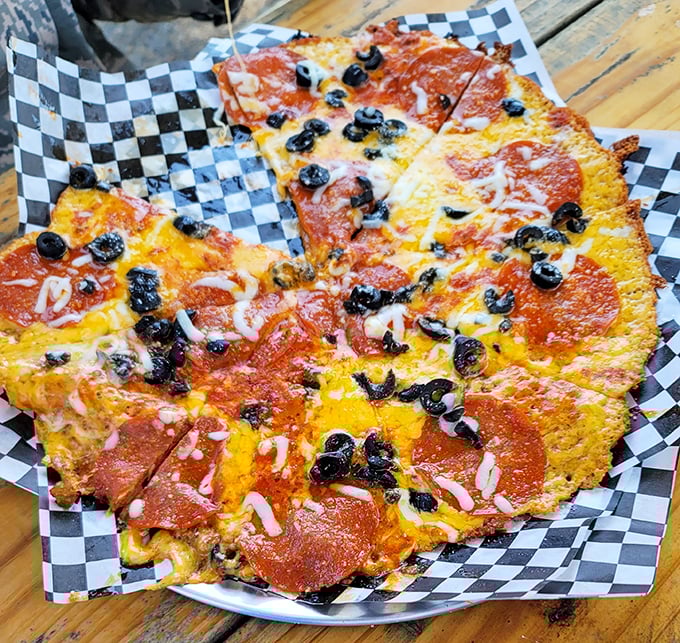 Pizza reimagined – crispy cheese forms the foundation for this saucy, olive-studded masterpiece that defies conventional pizza boundaries.