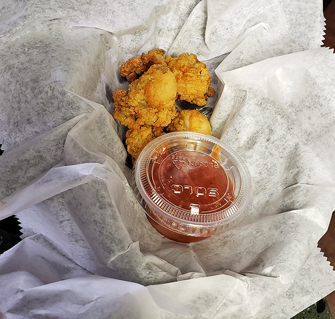 Golden-fried oysters nestled in paper with a side of cocktail sauce – proof that simplicity, when done right, is the highest form of culinary art.