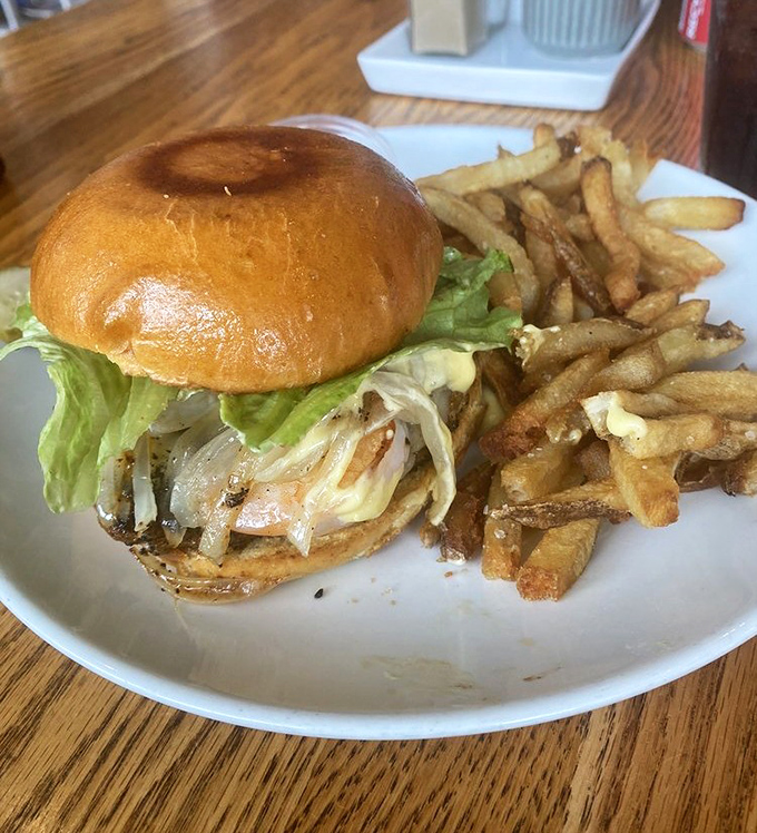 This isn't just a burger; it's a masterclass in balance—golden bun, caramelized onions, crisp lettuce, and those hand-cut fries deserve their own fan club.