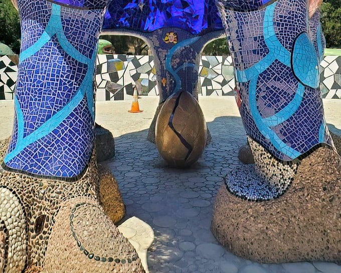 Beneath the blue legs of fantastical beasts sits a golden egg, as if the entire garden is one magnificent creature about to hatch a new idea.