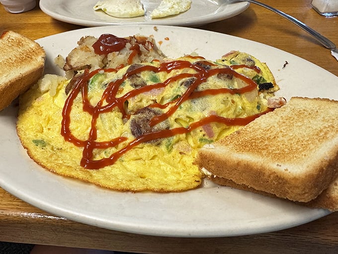 This isn't just an omelet—it's a morning masterpiece with a supporting cast of crispy potatoes and toast standing by to soak up every delicious bite.