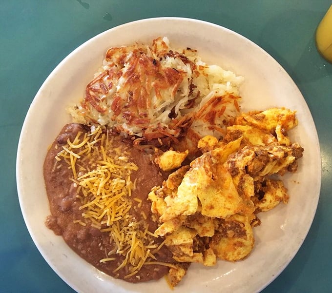 A plate that tells a story of comfort—refried beans with melty cheese, crispy hash browns, and scrambled eggs that look like they were made with actual care.