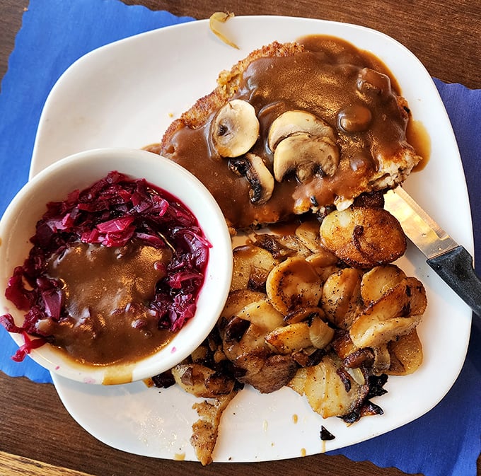 The Jager Schnitzel arrives like an ambassador from Bavaria—breaded cutlet draped in mushroom gravy with red cabbage providing that perfect tangy counterpoint.