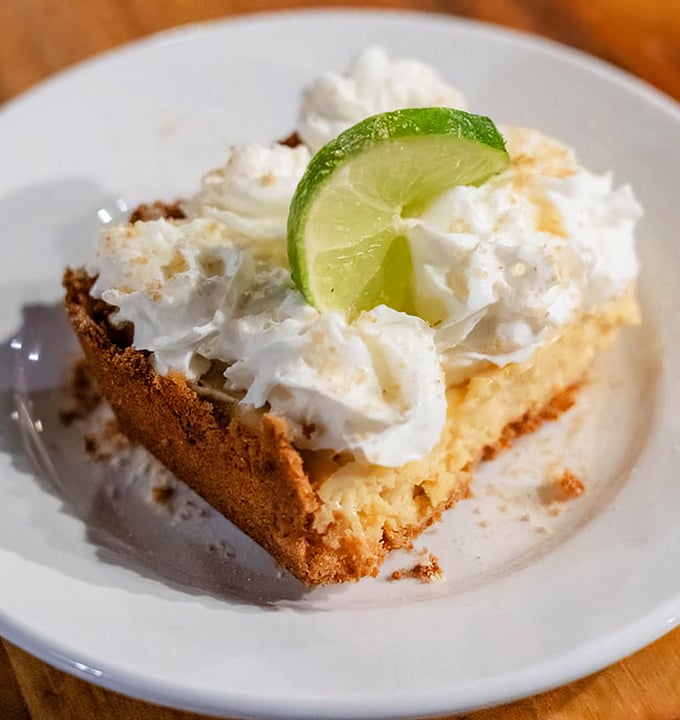 Key lime pie topped with a cloud of whipped cream and a lime slice that's not just garnish—it's the exclamation point on a sweet-tart masterpiece.