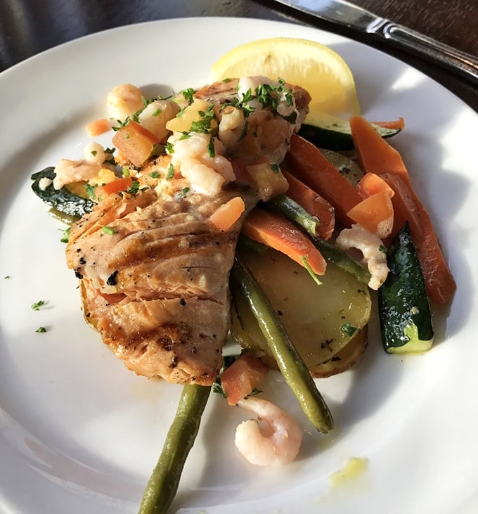 This king salmon doesn't just steal the show—it produces, directs, and writes it too. Perfectly seared and resting on a bed of colorful vegetables.
