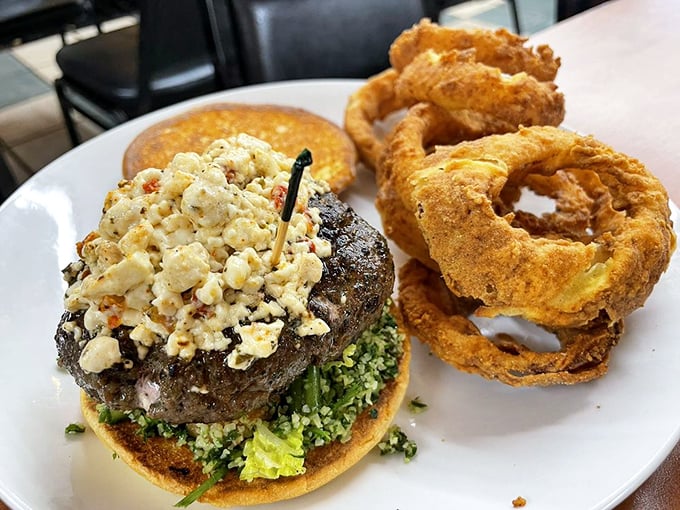 Not just any burger—this masterpiece topped with blue cheese crumbles and served with golden onion rings might just ruin all other burgers for you.