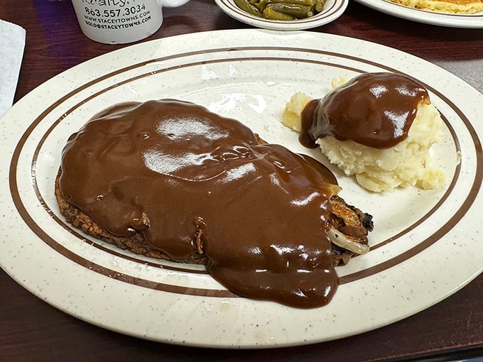 Liver and onions smothered in rich gravy with a side of mashed potatoes—a dish that separates casual diners from true comfort food connoisseurs.