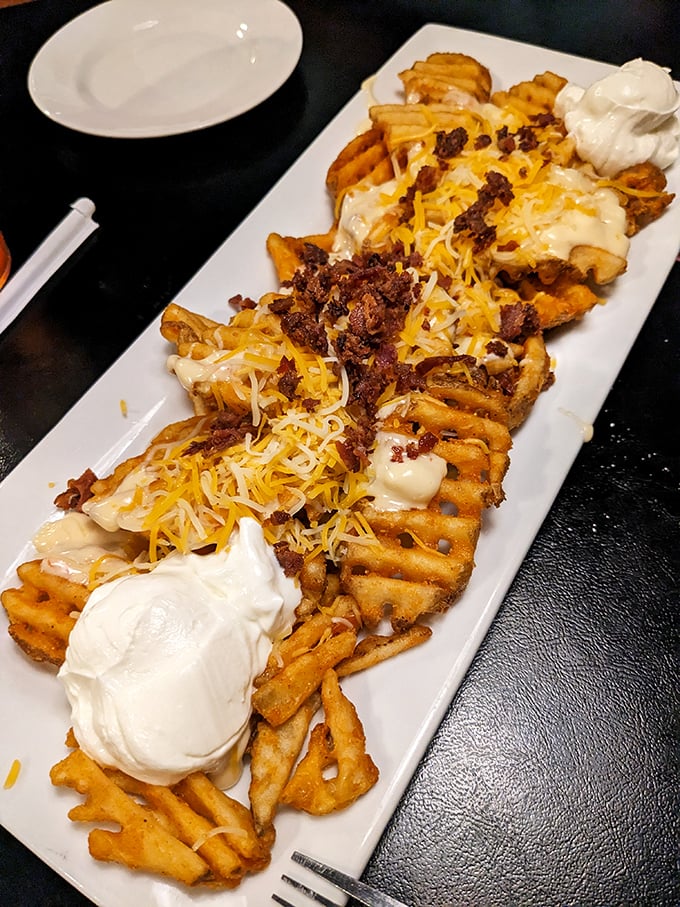 These loaded waffle fries aren't just a side dish—they're an engineering marvel of potato, cheese, bacon, and sour cream that demands your full attention.