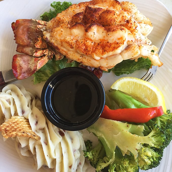 This perfectly grilled lobster tail sits atop a bed of greens with broccoli and mashed potatoes—proof that sometimes the simplest preparations let great ingredients shine.