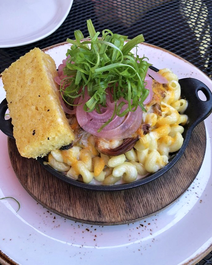 Mac and cheese elevated to an art form—complete with cornbread sidekick and pickled onions that cut through the richness like witty banter.