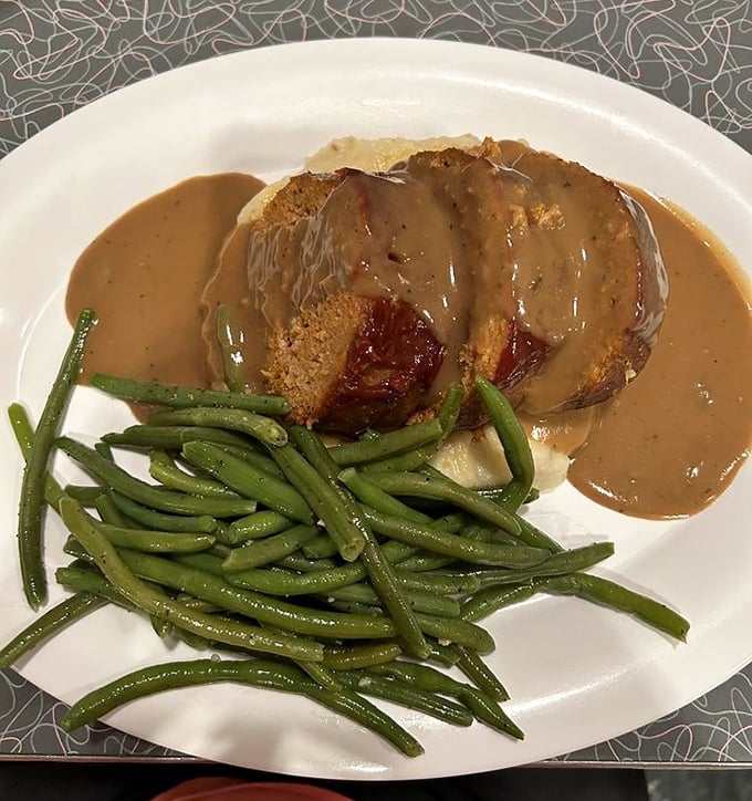 Meatloaf that doesn't just sit there looking pretty—it demands respect. Smothered in gravy that would make your cardiologist wince and your taste buds applaud.