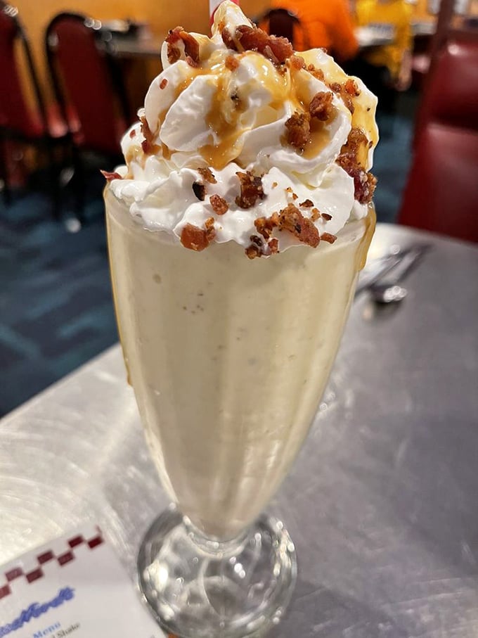 This isn't just a milkshake—it's a structural engineering marvel topped with whipped cream, caramel, and what appears to be bacon bits. Genius!