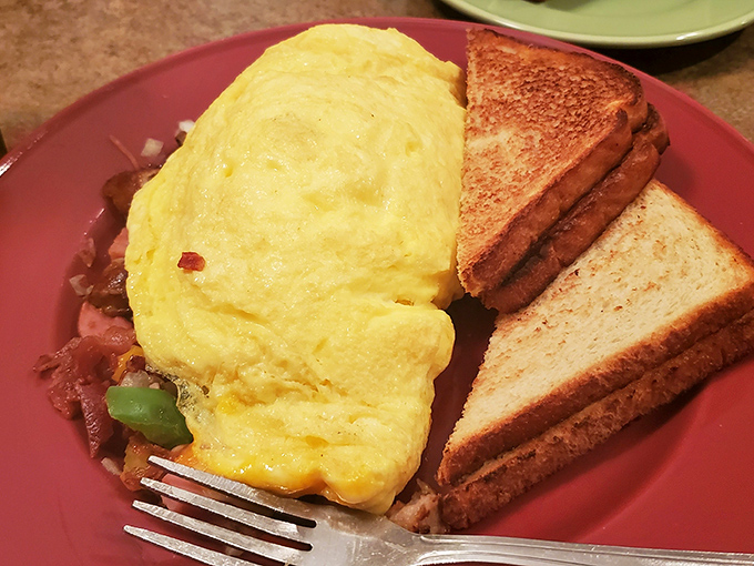 This omelet doesn't just sit on the plate—it commands attention. Fluffy eggs embracing savory fillings with perfectly toasted bread standing guard.