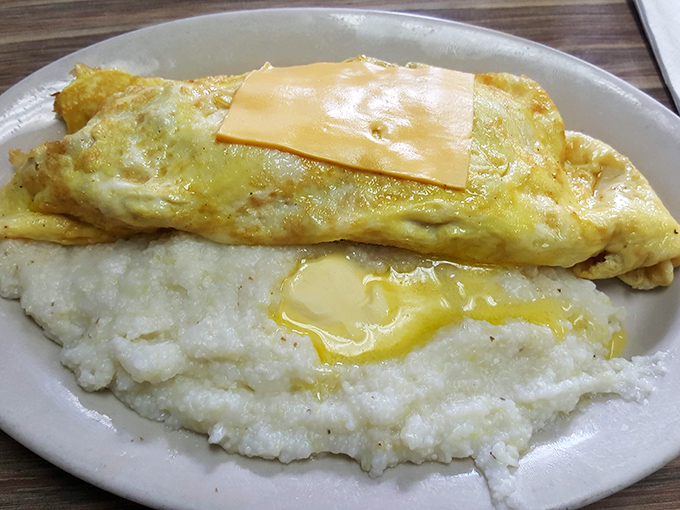Cheese oozing over a perfectly folded omelet atop a cloud of buttery grits—proof that simplicity, when done right, is the ultimate sophistication.