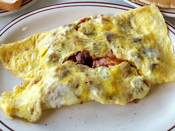 This isn't just an omelet—it's a masterclass in breakfast architecture. Perfectly folded eggs housing a treasure trove of ham and cheese. Morning magic on a plate.