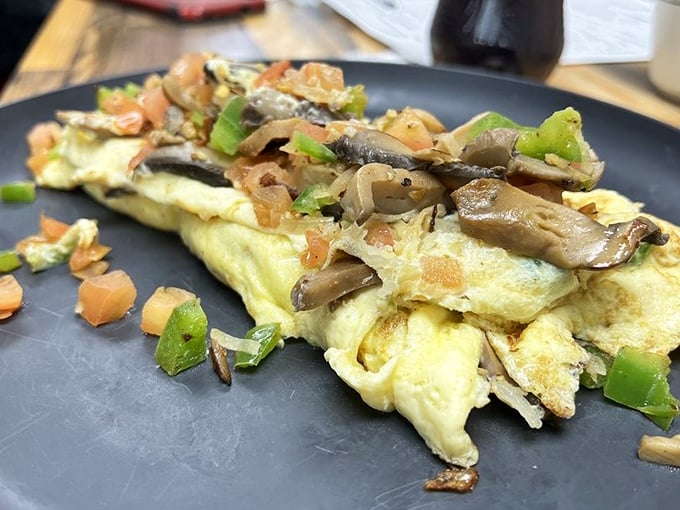 An omelet that doesn't just sit on the plate—it commands attention with fresh vegetables and perfect execution. Breakfast elevated beyond the ordinary.