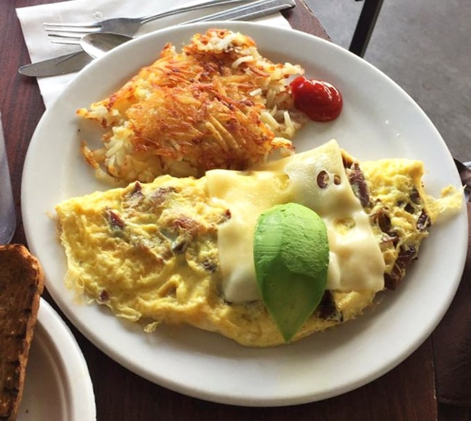 An omelet that doesn't need fancy French techniques—just cheese, perfectly crispy hash browns, and a slice of avocado playing king of the mountain.