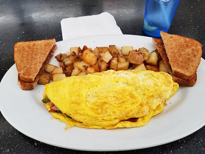 Behold the perfect omelet—sunshine-yellow, expertly folded, and keeping company with home fries that could make a potato farmer weep with pride.