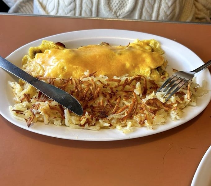 This omelet doesn't just hang off the plate—it establishes territorial claims on the hash browns, which have been perfectly crisped to golden perfection.