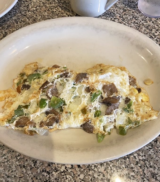 This omelette doesn't just contain mushrooms and peppers—it showcases them like treasured jewels in a fluffy egg crown.