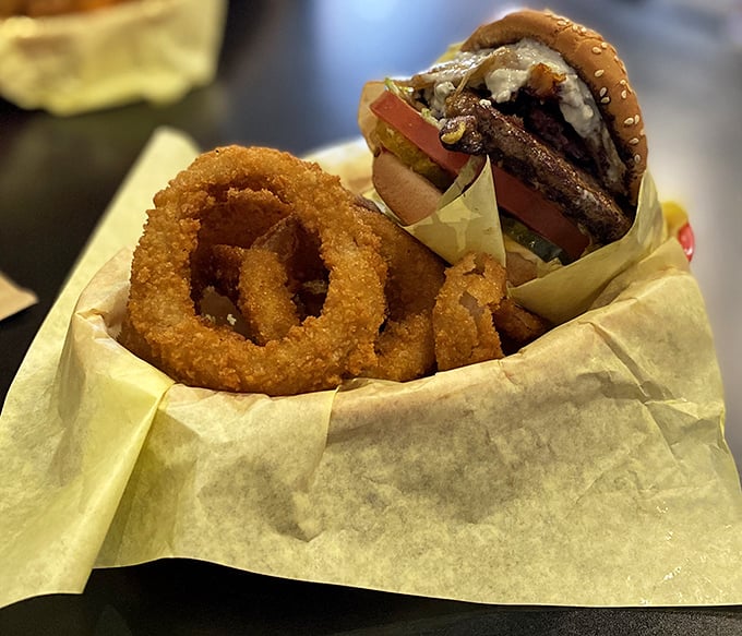 Golden rings of happiness alongside a burger that requires both hands and possibly a building permit. Worth every delicious calorie.