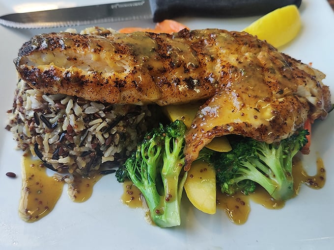This isn't just grilled fish – it's pan-seared rockfish performing a delicate balancing act atop wild rice and vegetables, all dressed in a sauce that deserves its own fan club.