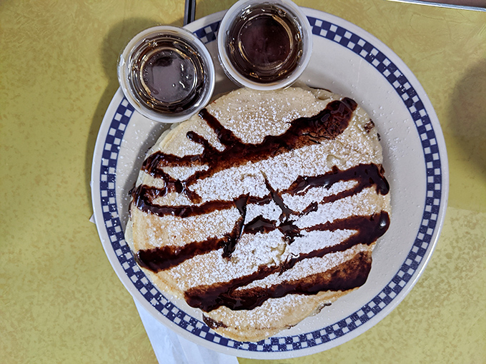 Pancakes drizzled with chocolate sauce and dusted with powdered sugar—proof that sometimes the universe's greatest pleasures come in simple, circular form.